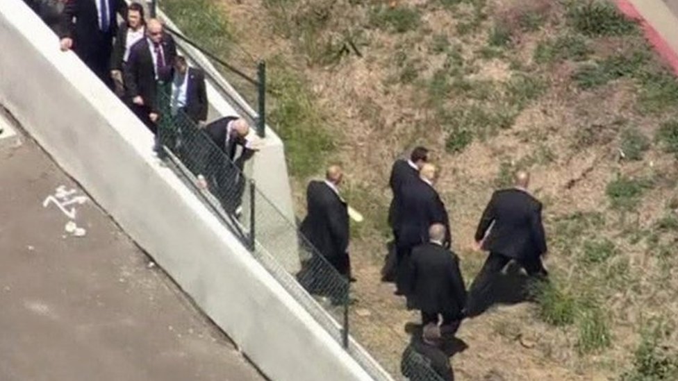 Donald Trump jumps highway barrier at rally to avoid protesters - BBC News