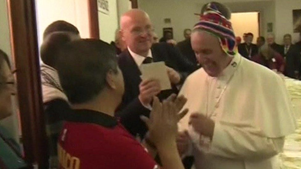 Pope tries on woolly hat during soup kitchen visit - BBC News
